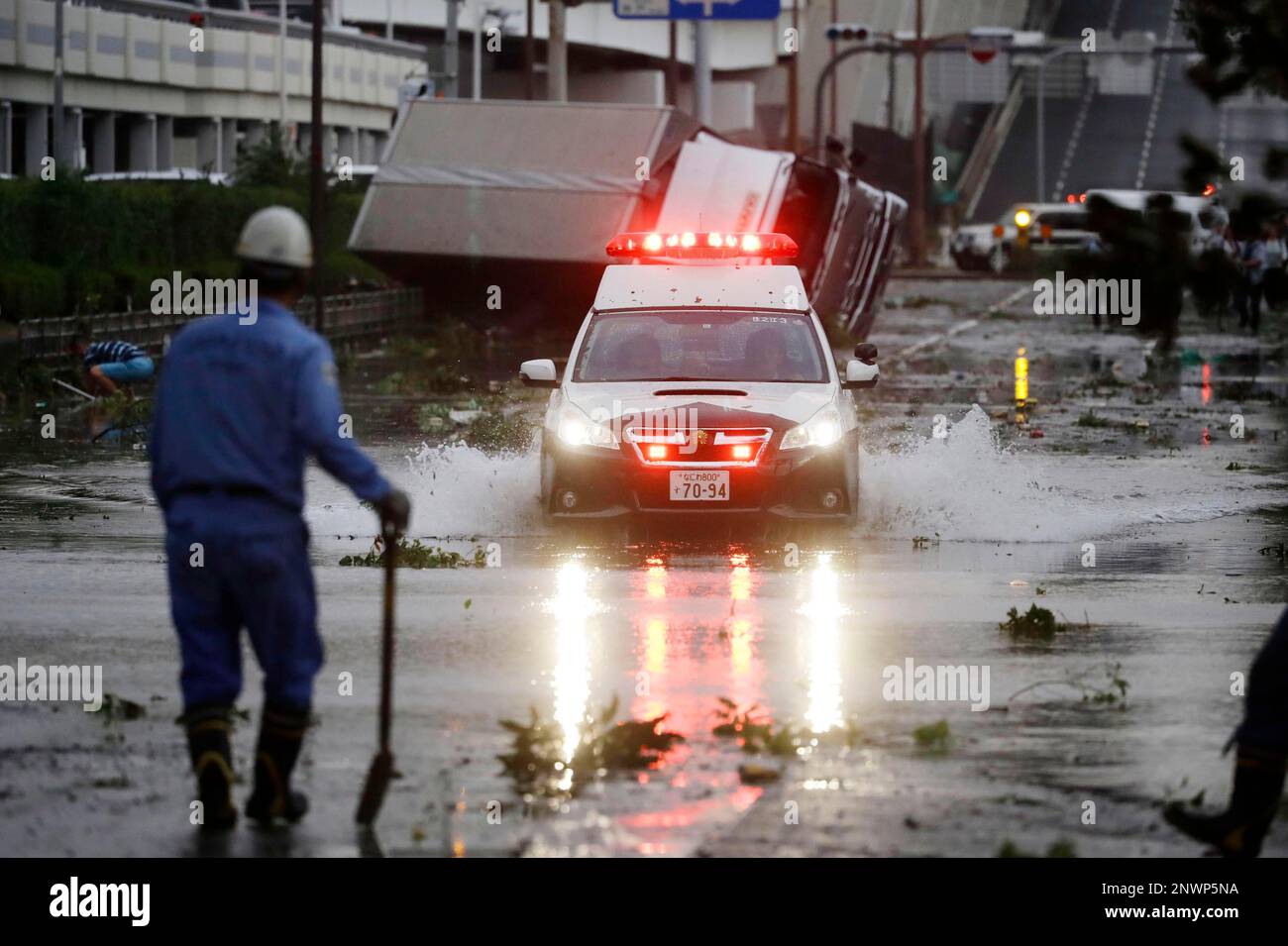 A police car makes through a flooded road following a powerful typhoon ...