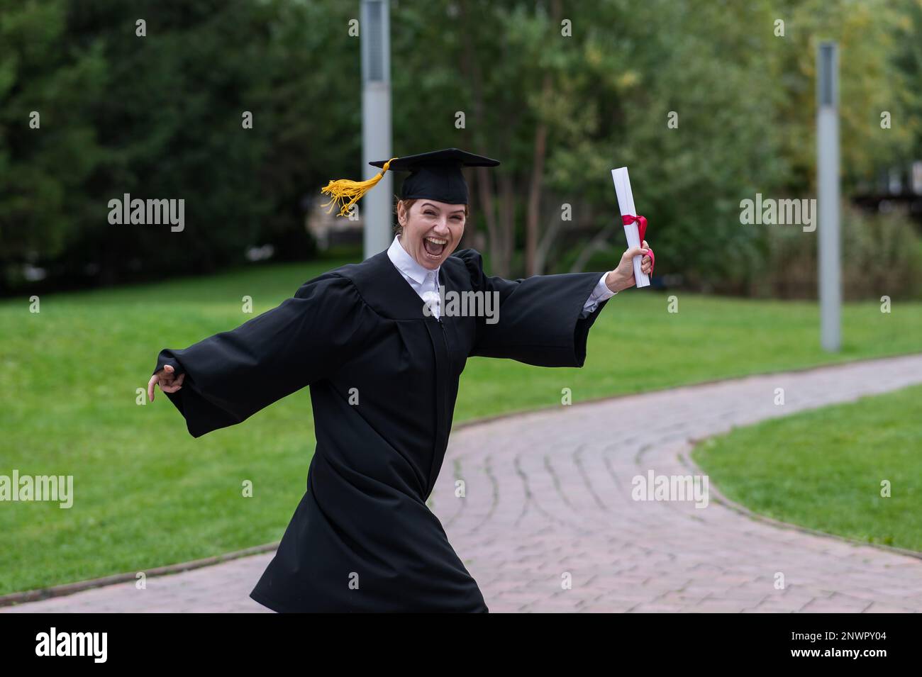 Caucasian woman in graduate gown dancing for joy outdoors Stock Photo ...