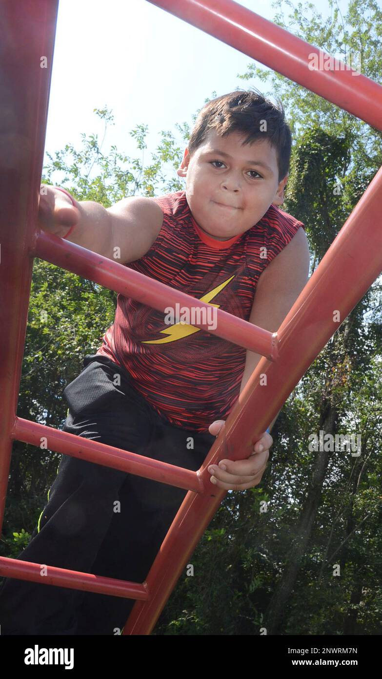 Seven-year-old Alfredo Perez climbs around on a set of curved monkey ...