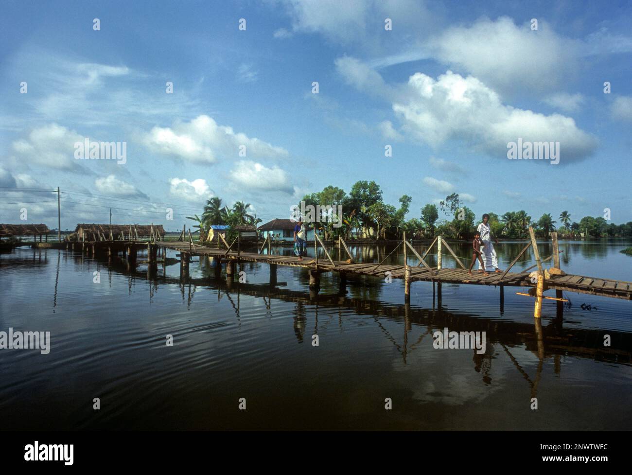 A scene of people crossing the backwater on the wooden bridge located ...
