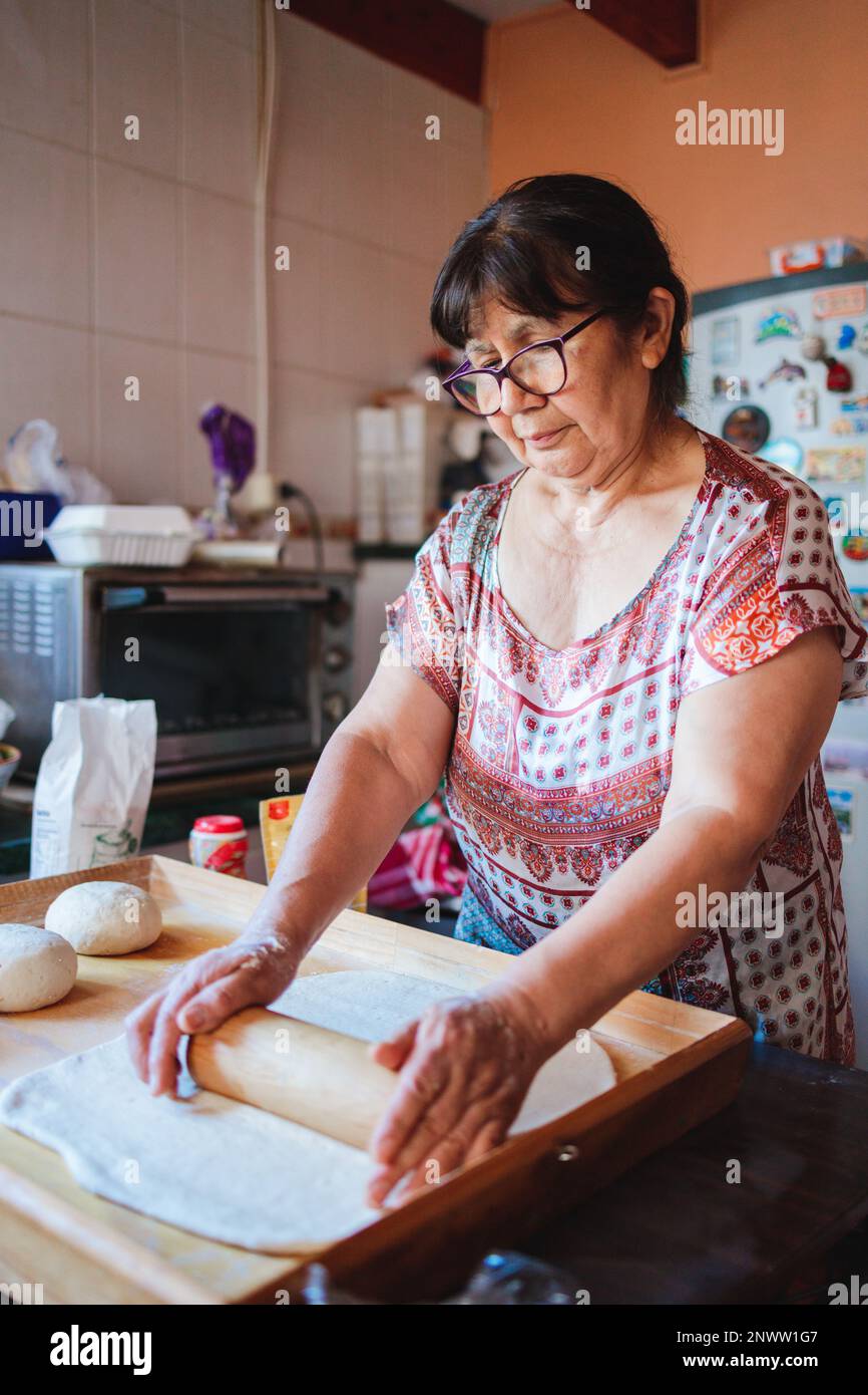 Portrait of an senior hispanic woman cooking homemade bread in her ...