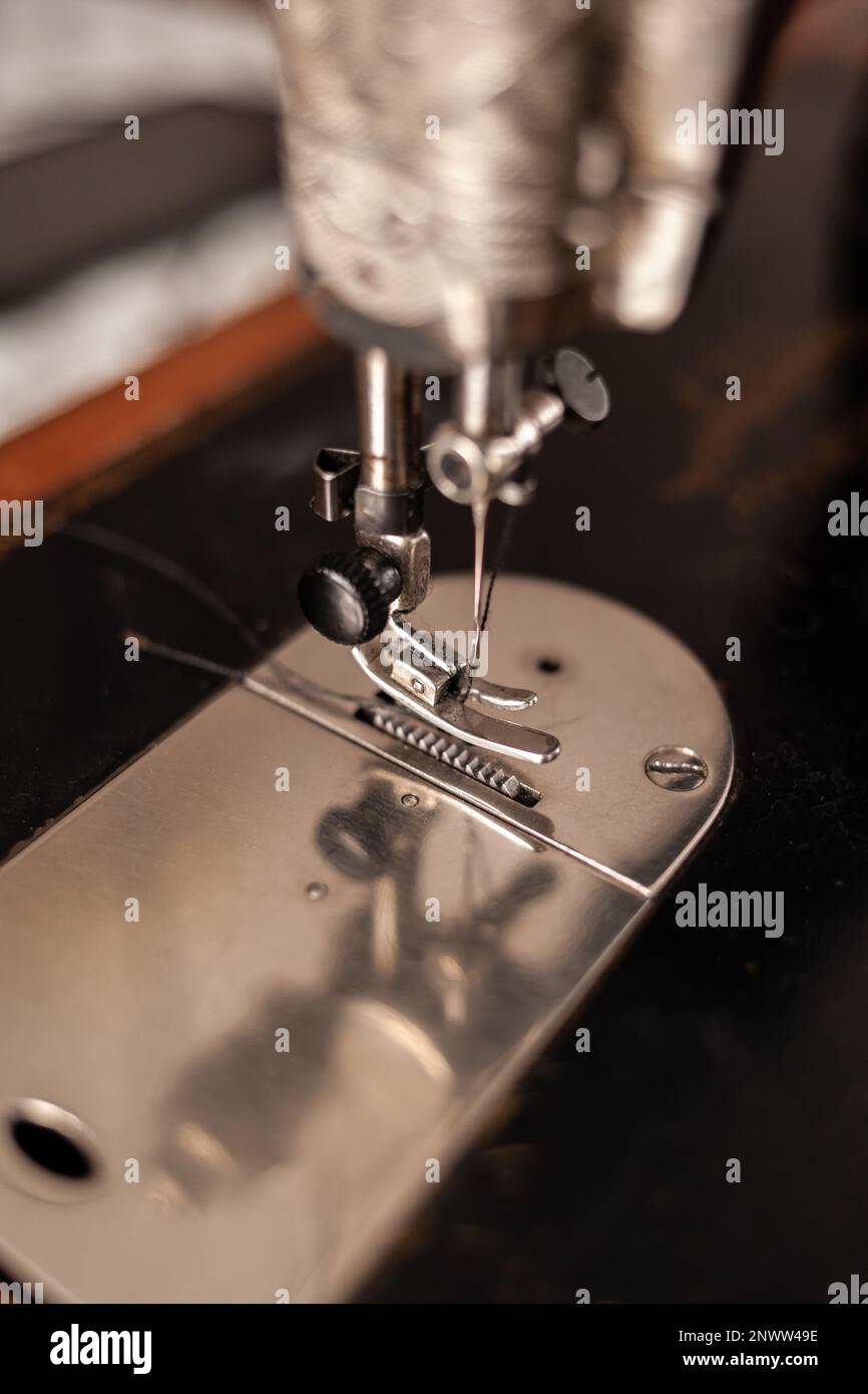 An old sewing machine stands on the table at home ready to work and sew ...