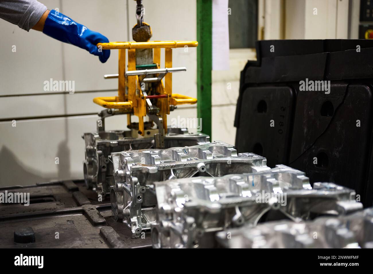 Warehouse of an automobile plant, a worker lifts the cylinder block of ...