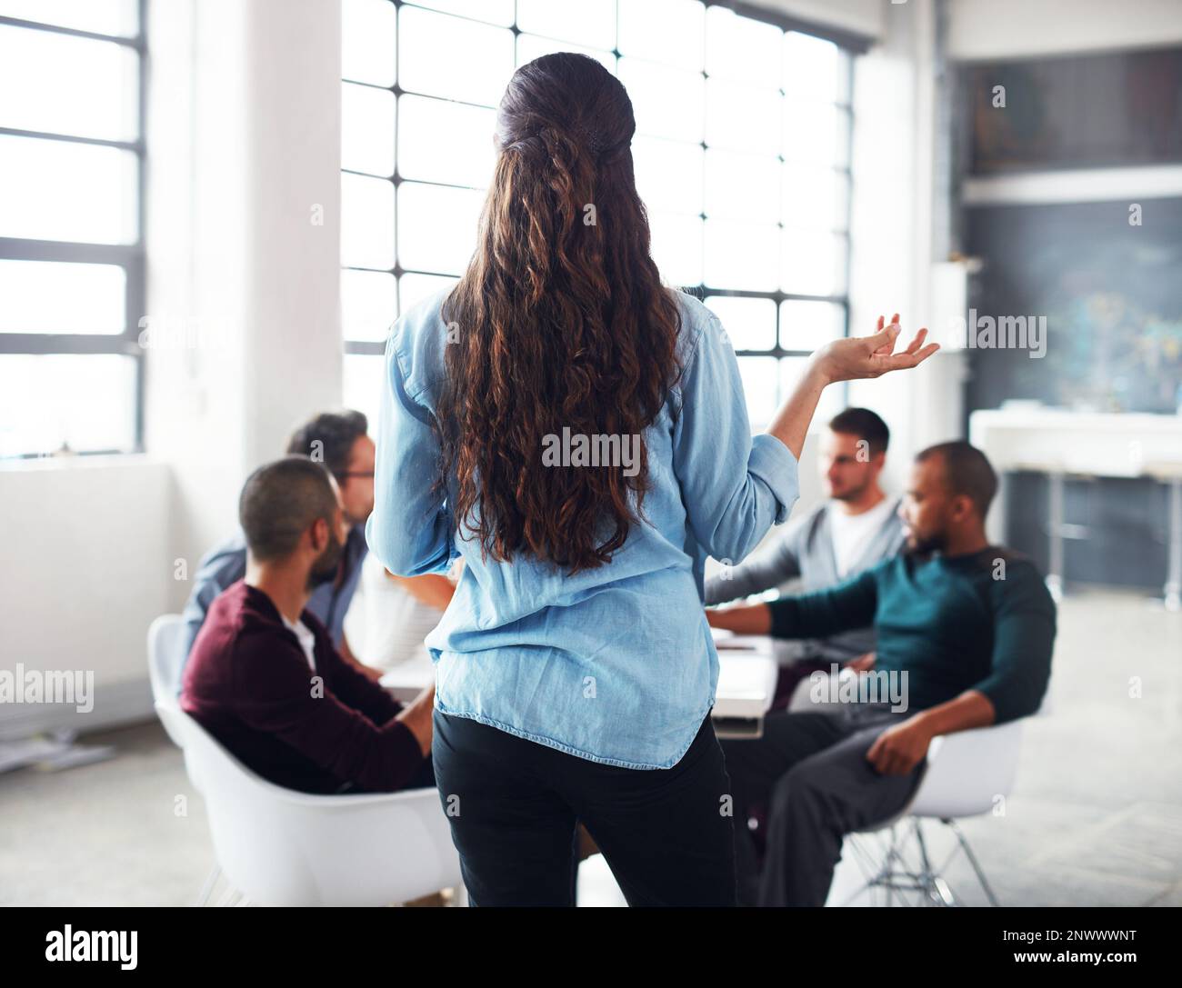 The creative process. Rearview shot of a woman giving a presentation to ...