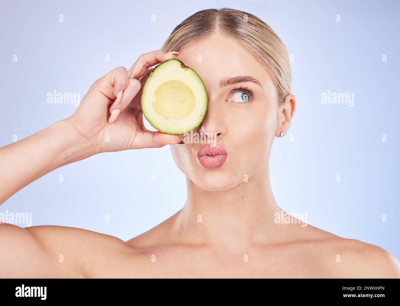 Face, skincare and woman with avocado in studio isolated on a blue ...