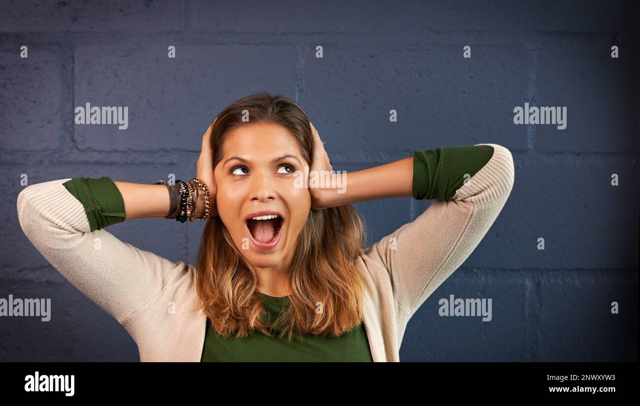 Thats insane. a young woman covering her ears against a brick wall ...