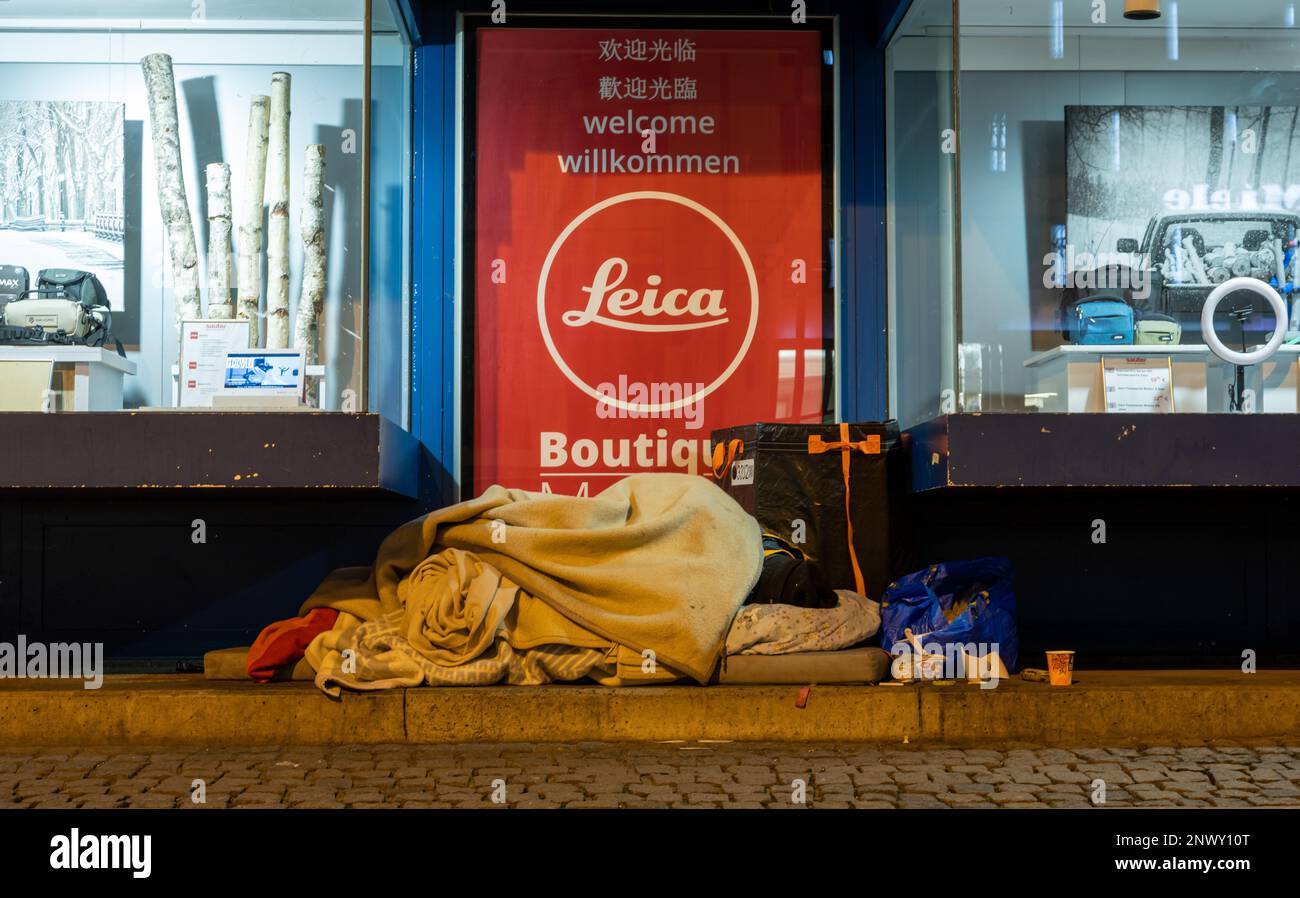 Munich, Germany. 01st Mar, 2023. A homeless man sleeps in the light of ...