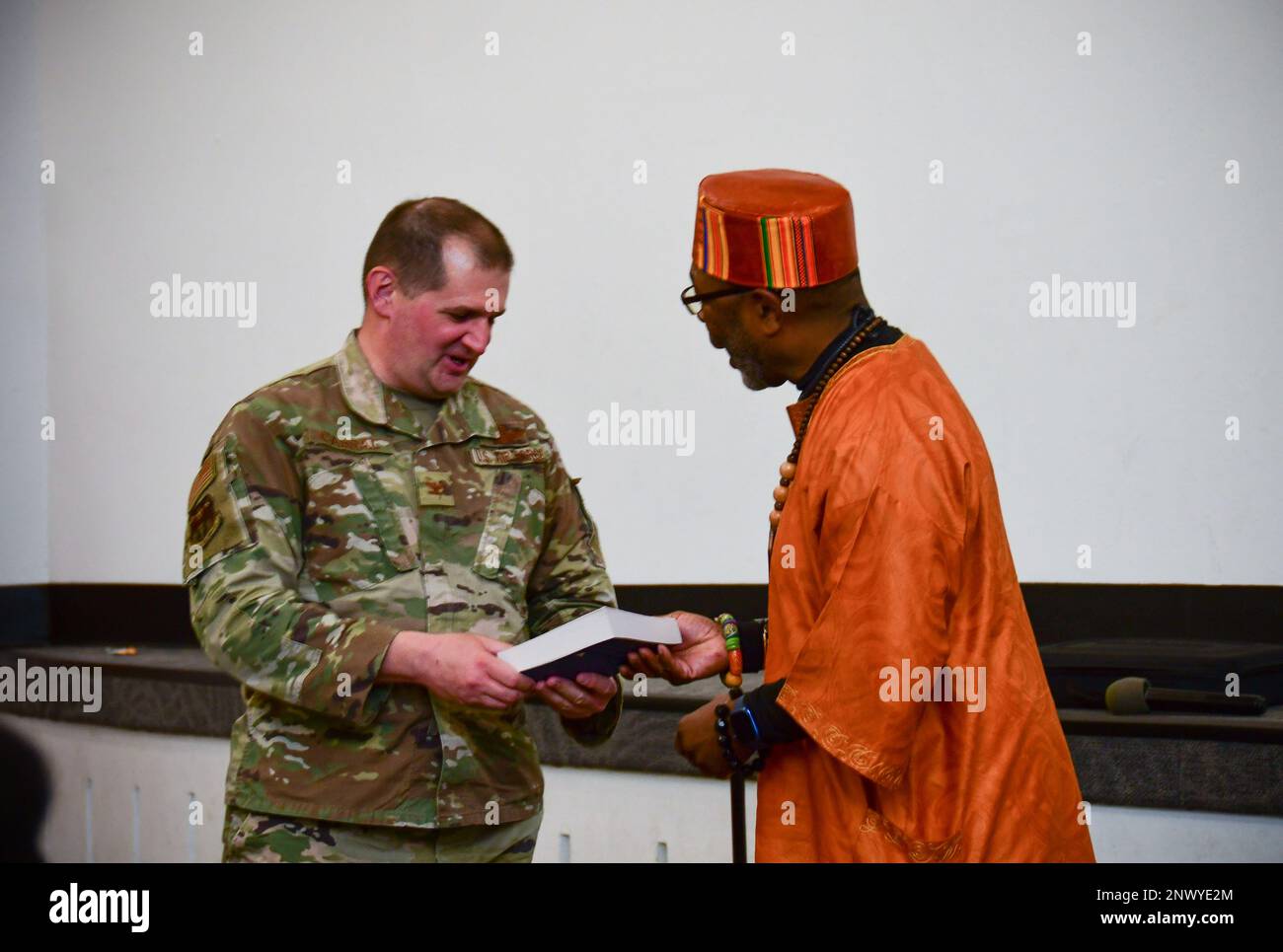 Retired Master Sgt. Rodney Smith hands a book to Col. Michael Cabral ...
