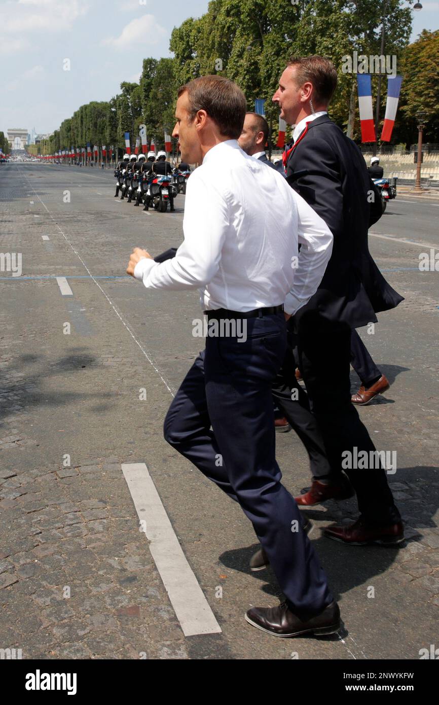 French President Emmanuel Macron, flanked by bodyguards, runs to greet ...