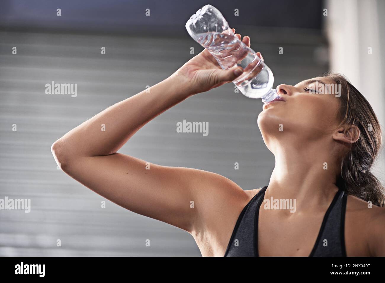 Keeping her body hydrated. a young woman drinking from her water bottle ...