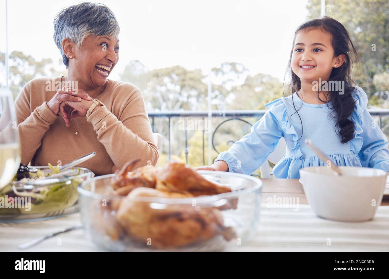 Family, food and grandmother with girl a table for lunch, part or social gathering on a patio ...