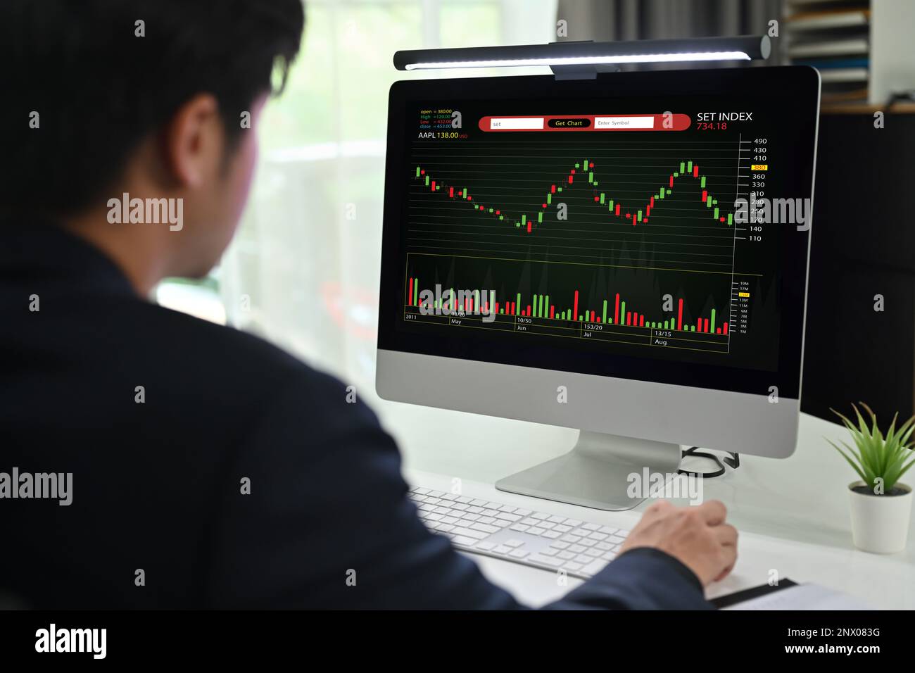 Back view of young trader in formal wear sitting in his office in front ...
