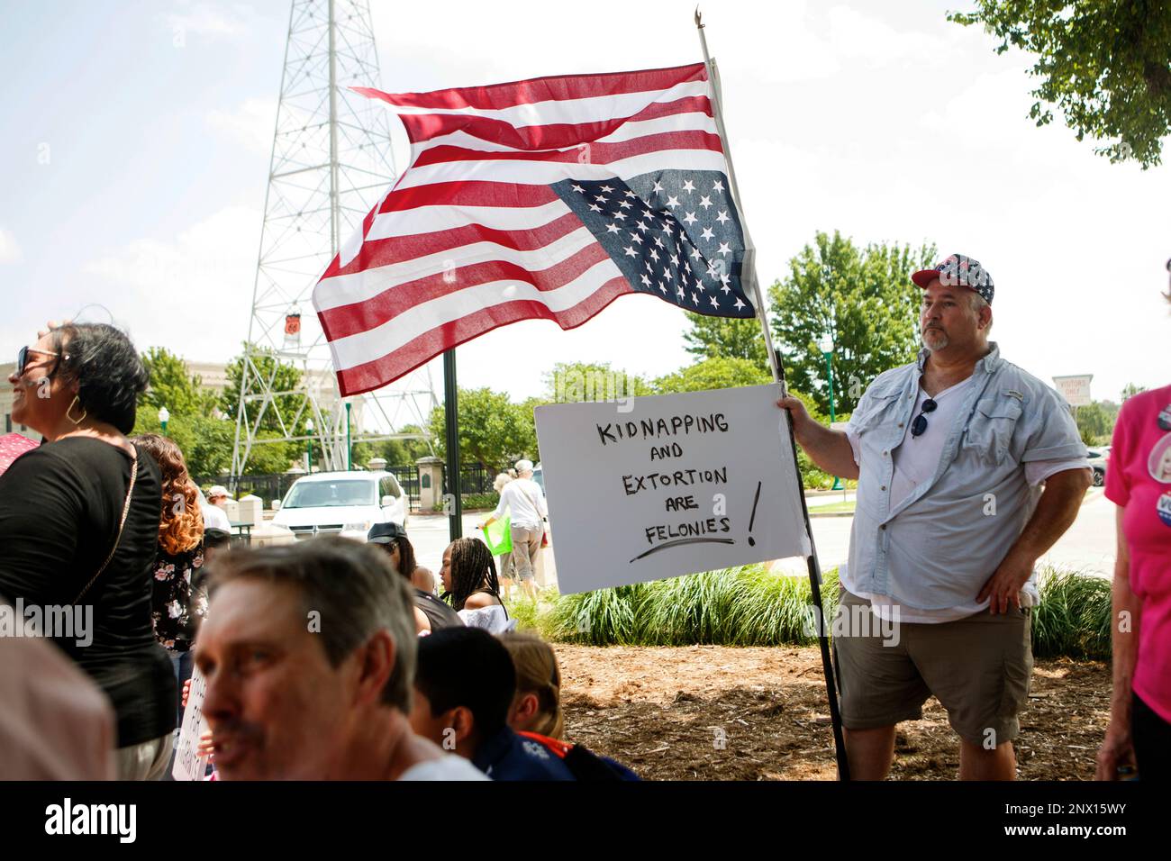 Tim Thacker holds a sign and an American flag turned upside down at the ...