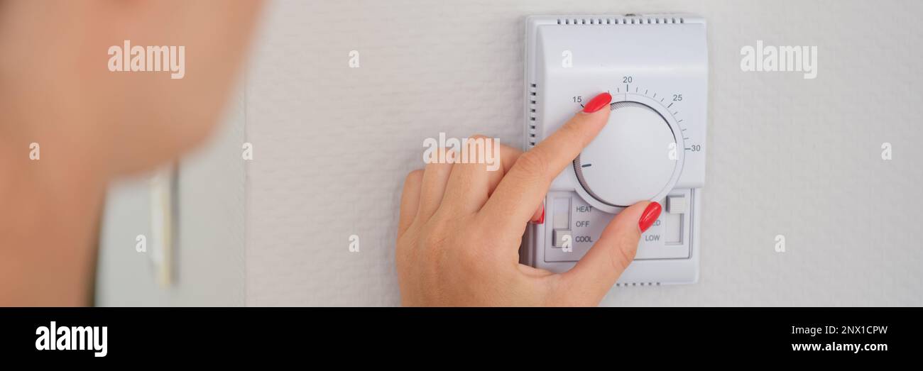 Hand adjusts button of the control unit of heating and cooling system ...