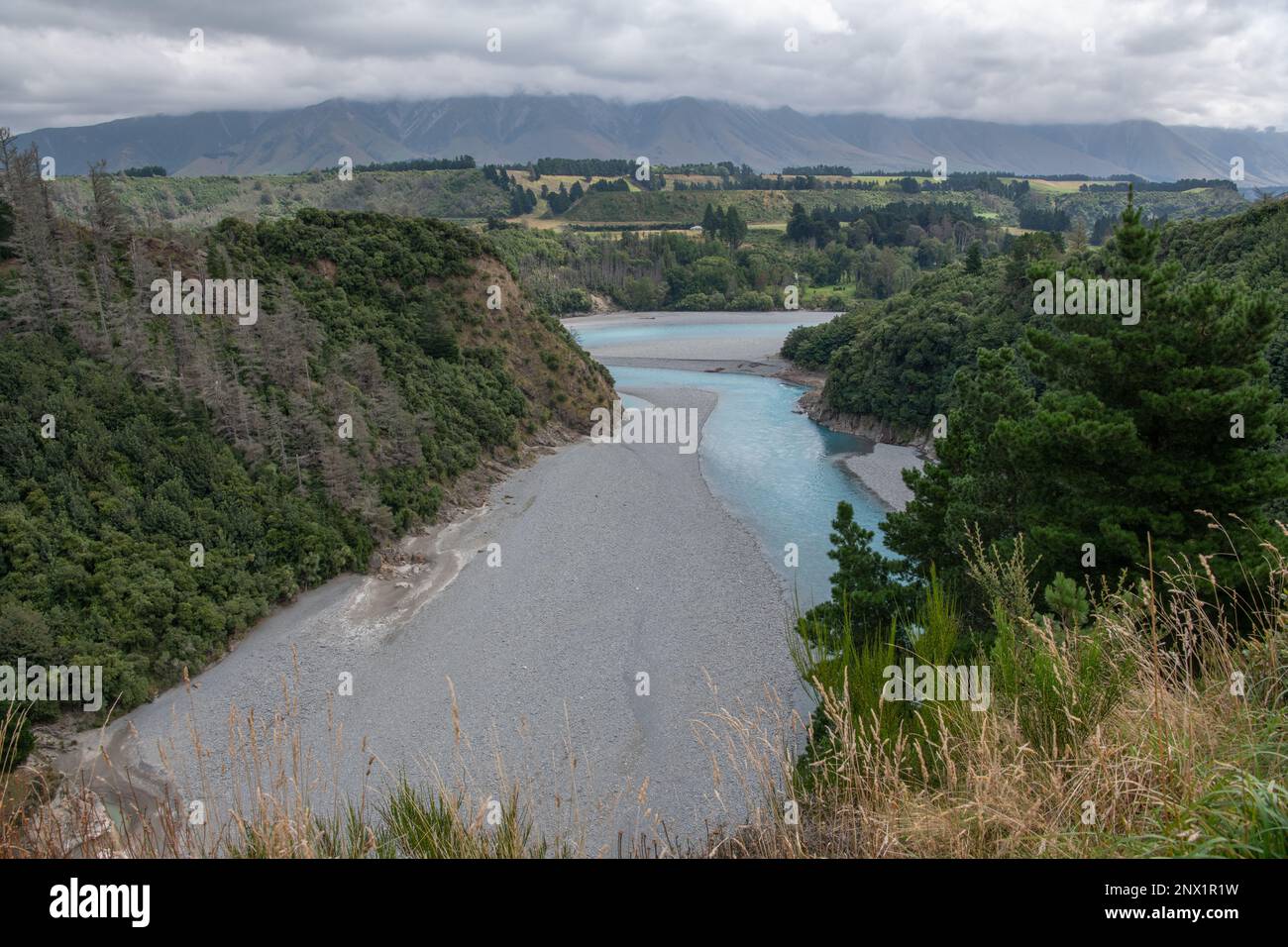 The blue water of the Rakaia river as it flows through the hilly forest ...