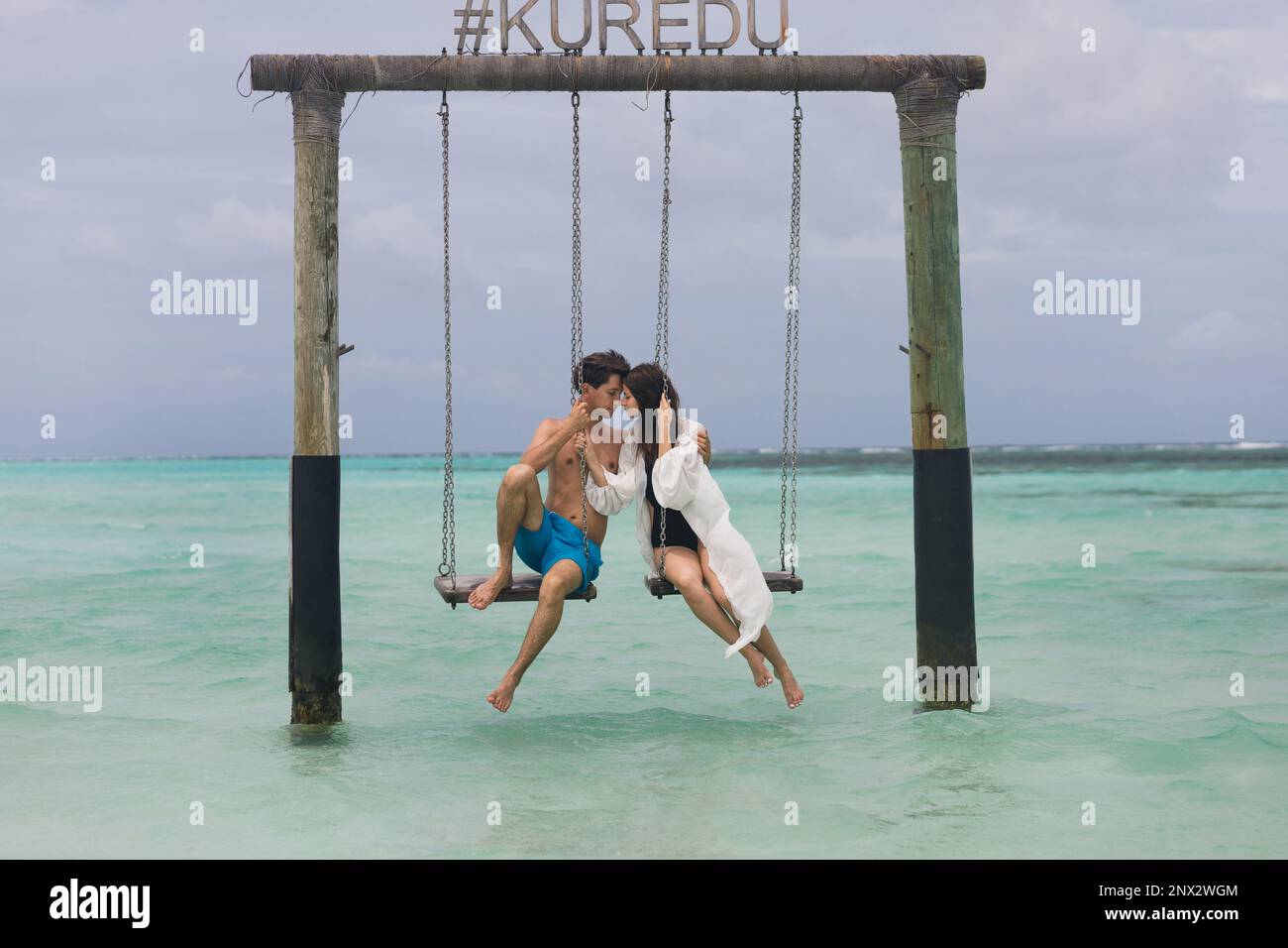 A young couple is swinging on a swing on a tropical beach in the ...