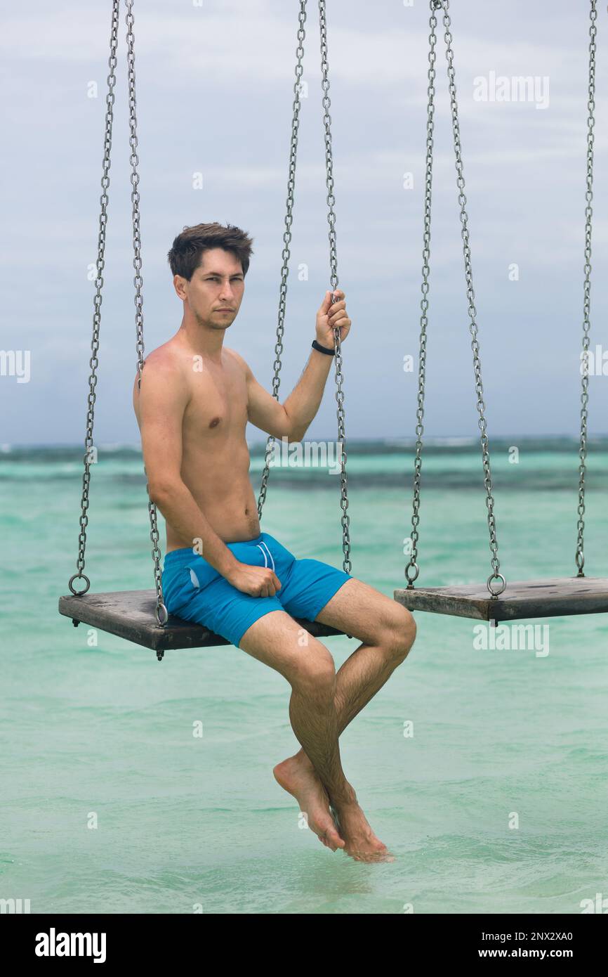 Male tourist sitting on a swing on the beach, Maldives Stock Photo - Alamy