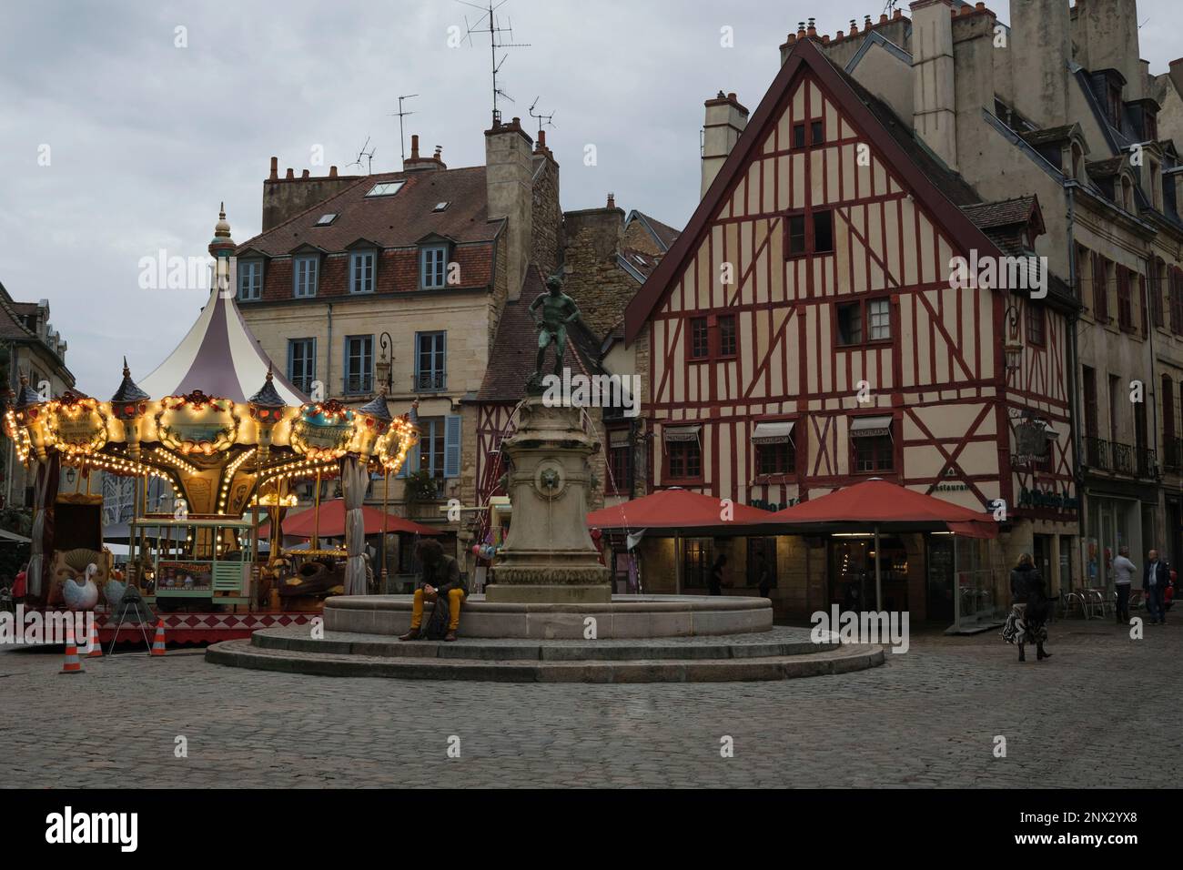 Square with old fountain and carousel in the center of Dijon at night ...