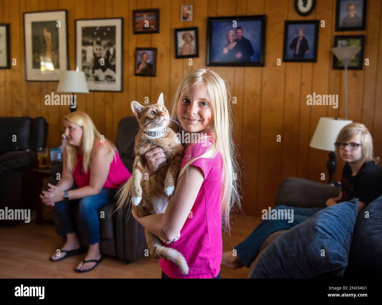 Brielle Beyer, 11, center, holds the family cat in the living room of ...
