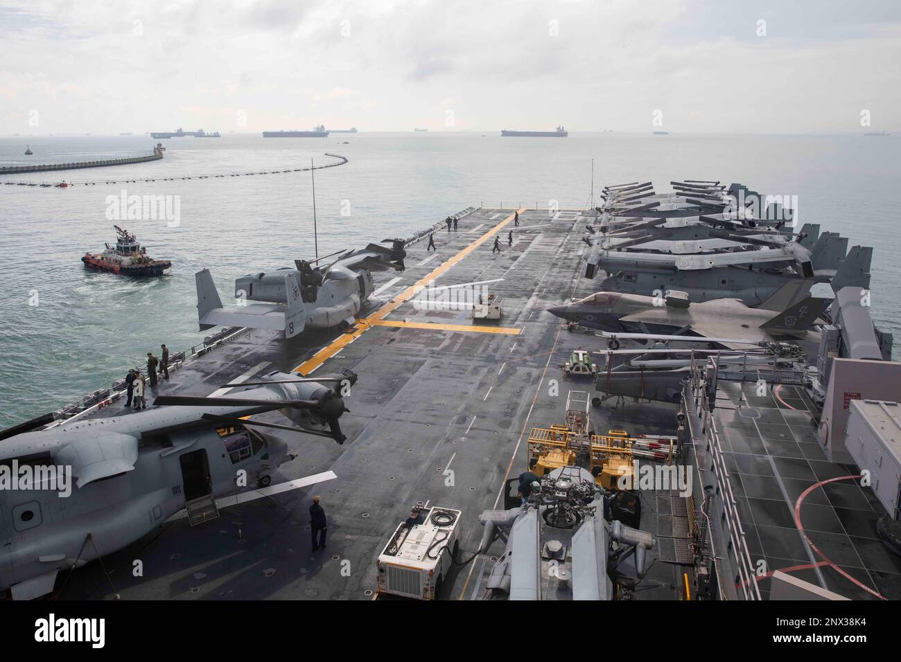 230210-N-YR119-1013 A tug boat guides amphibious assault ship USS Makin ...