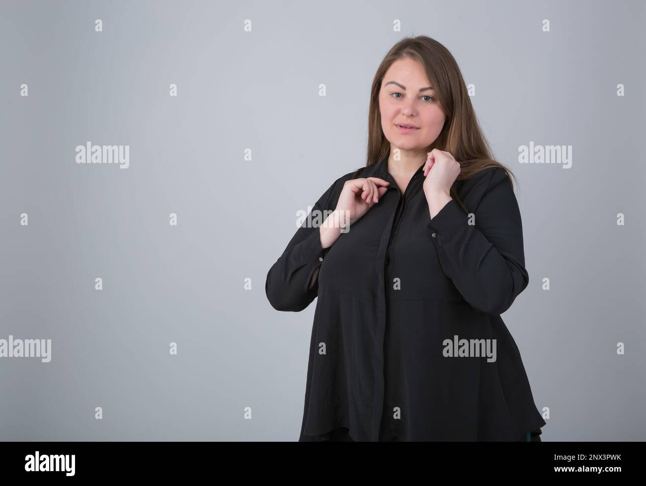 Good looking overweight woman in black casual shirt posing in studio ...