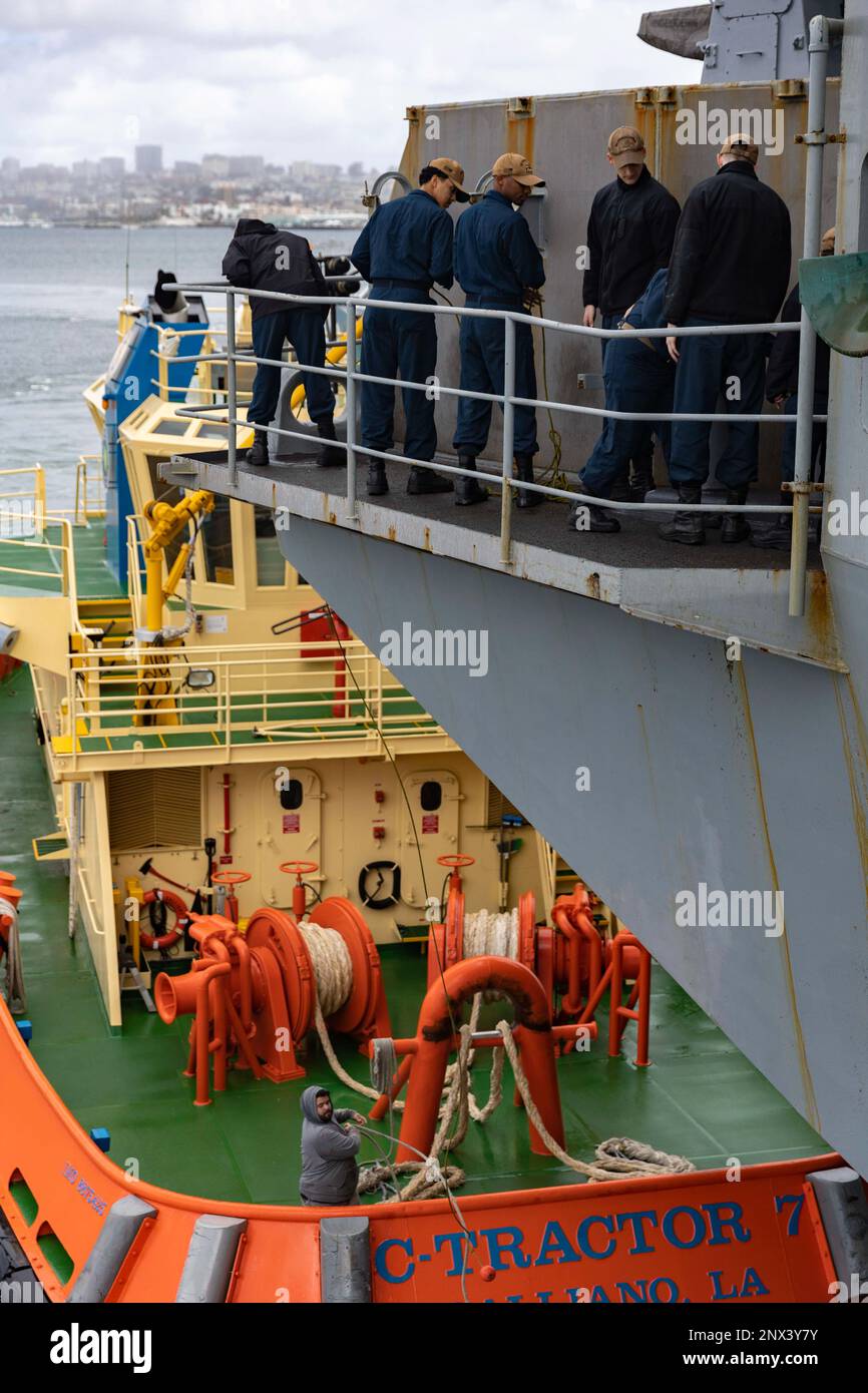 Sailors feed line to a C-Tractor 7 tugboat on the fantail aboard the ...