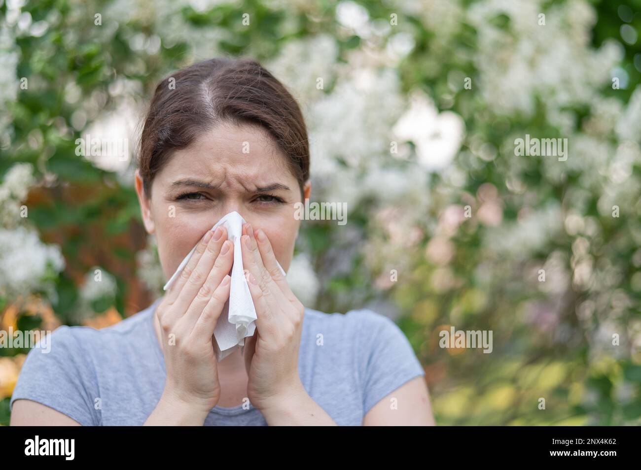 Caucasian woman suffers from allergies and blows her nose into a napkin ...