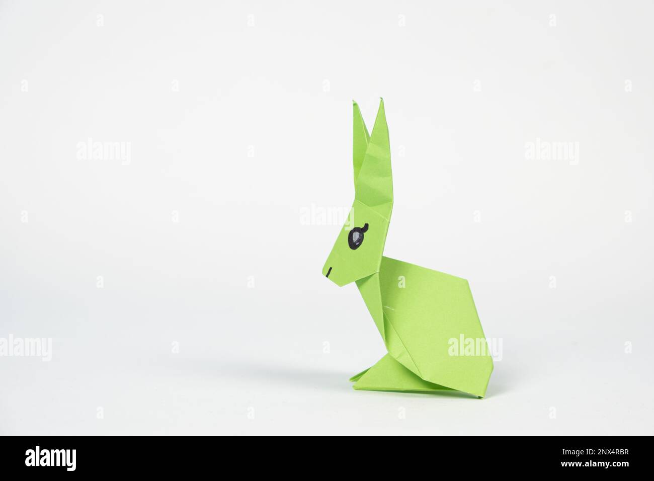 A green origami rabbit on a white background. Crafts for Easter, fold ...