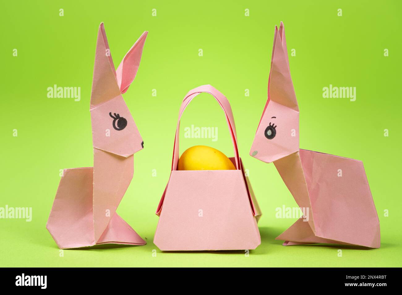 Easter origami - two paper bunnies and an egg, green background. Crafts ...
