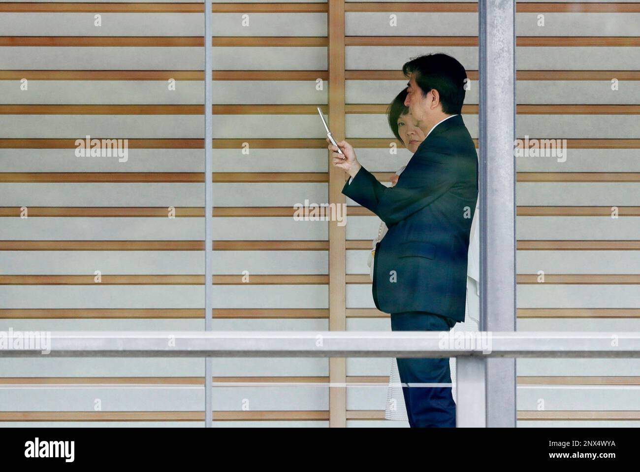 Japanese Prime Minister Shinzo Abe checks his mobile phone next to his ...