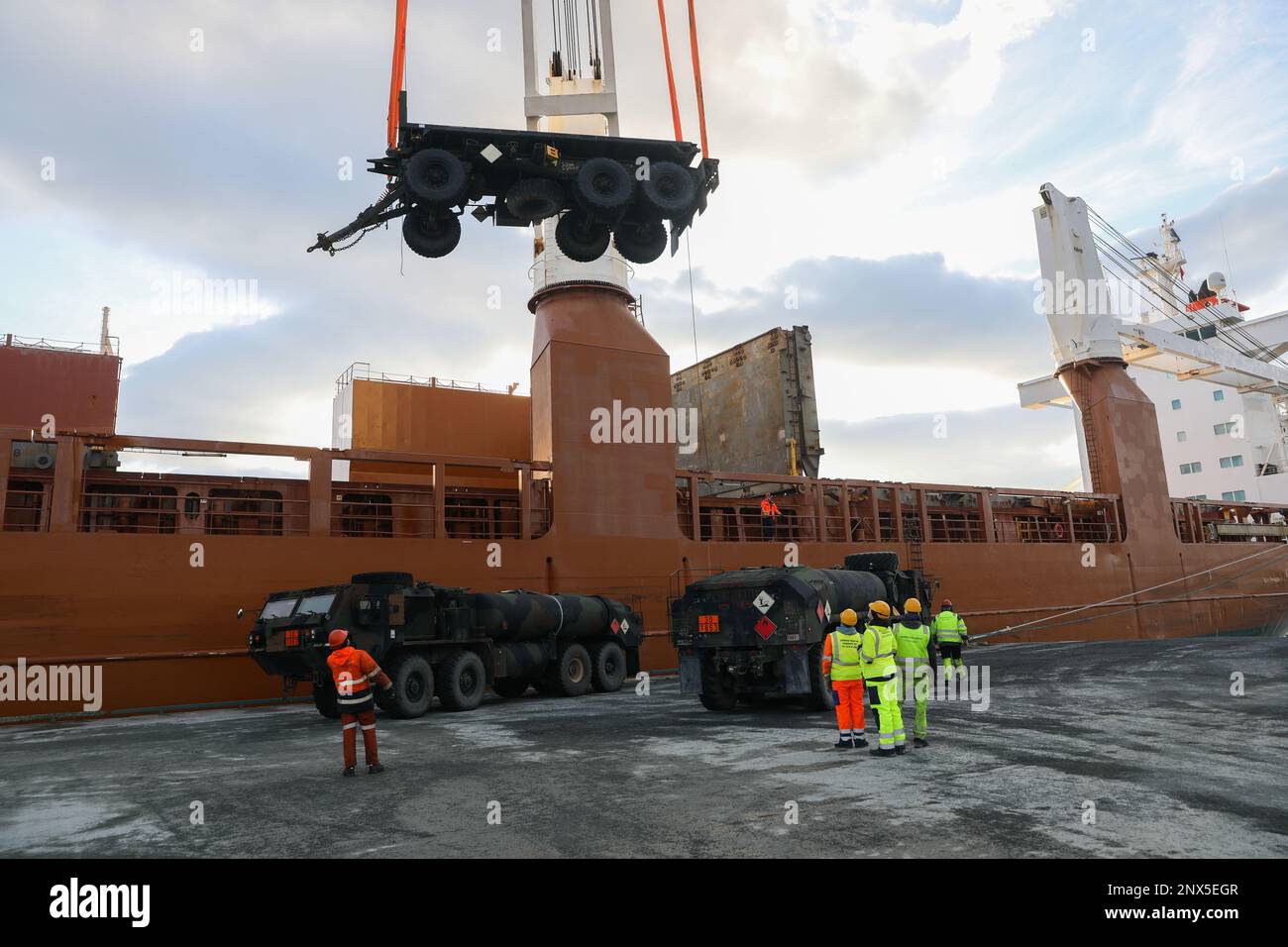 An M1076 3-Axel Flatbed is lifted out of the ship and transported to ...