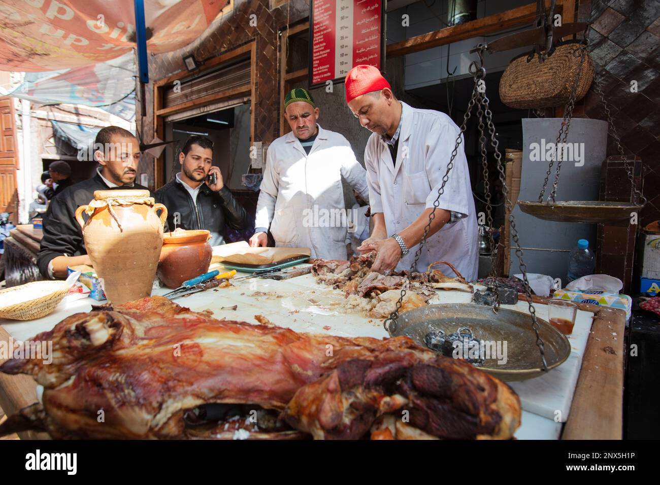 Marrakech, Morocco – February 25, 2023: Butcher weighs roast meat in ...
