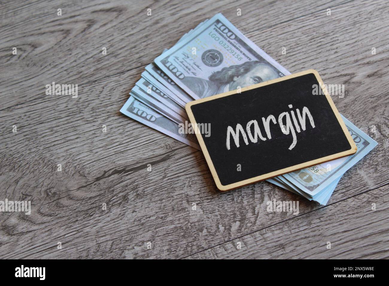 Money and chalkboard with text MARGIN. Business concept Stock Photo - Alamy