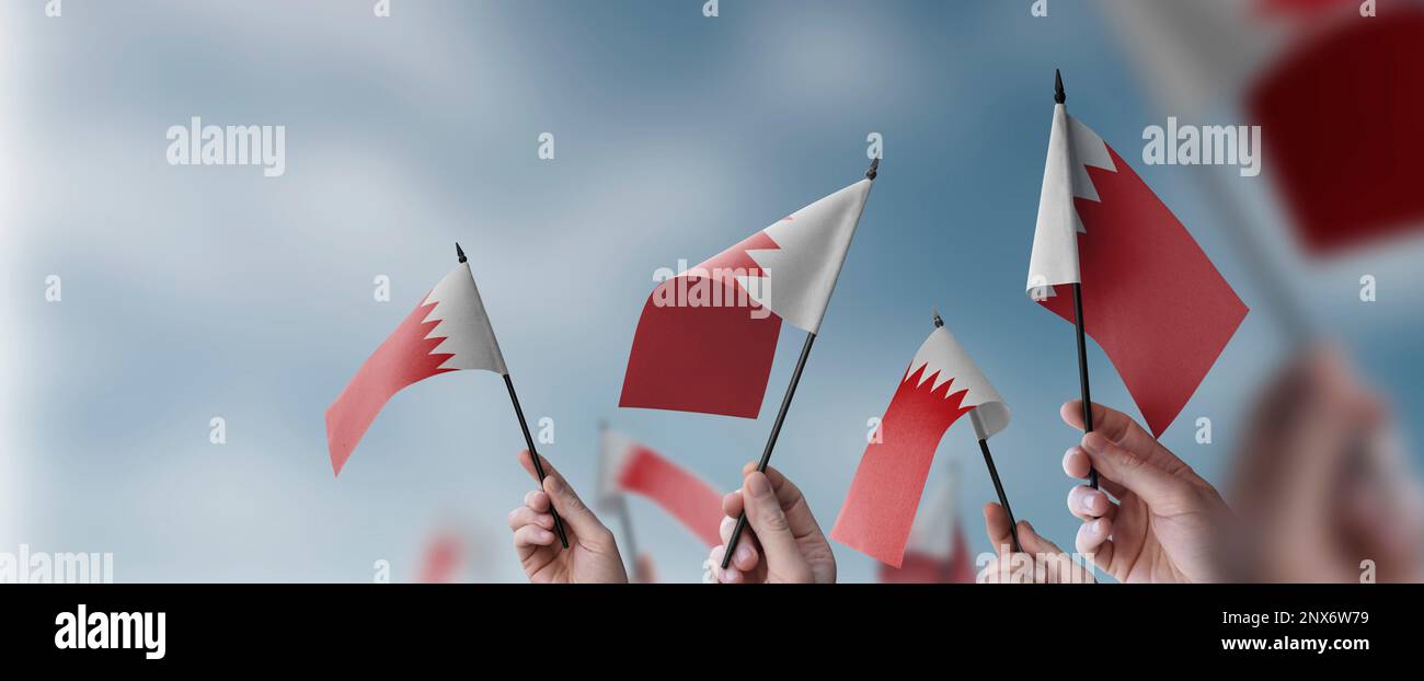 A group of people holding small flags of the Bahrain in their hands ...