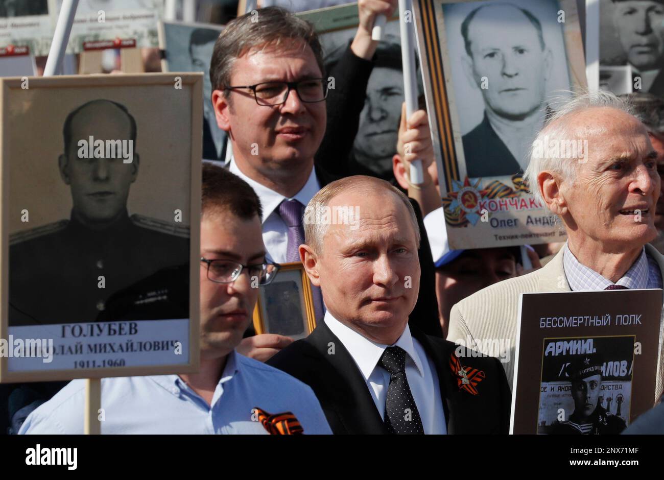 Russian President Vladimir Putin, center, holds a portrait of his ...