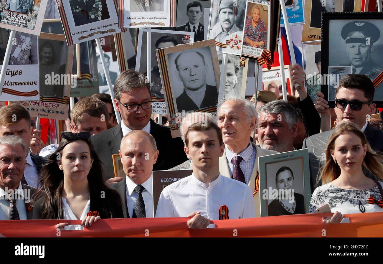 Russian President Vladimir Putin, third left, holds a portrait of his ...