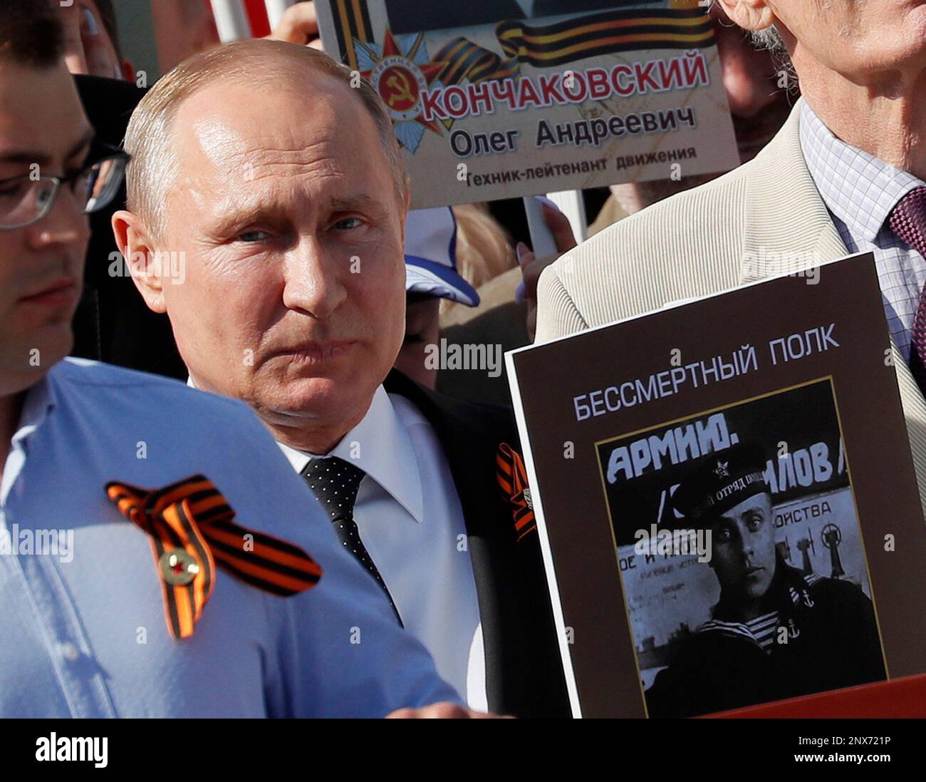 Russian President Vladimir Putin, right, holds a portrait of his father ...