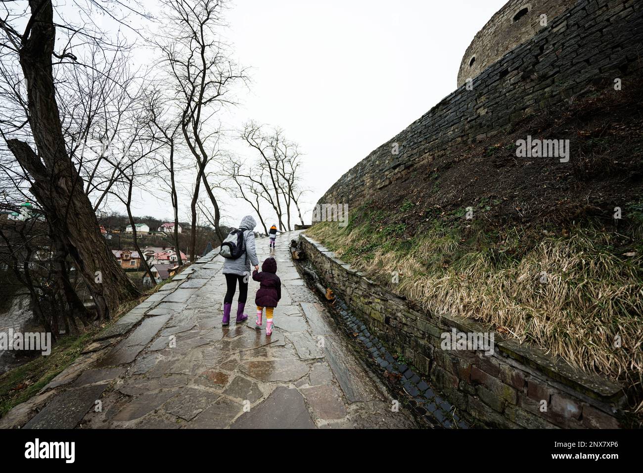 Mother and girls walk up the wet path to an ancient medieval castle ...