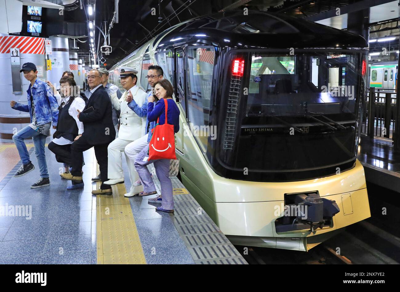 People pose for photograph in front of Train Suite Shiki-shima, the E001 series luxury sleeper ...