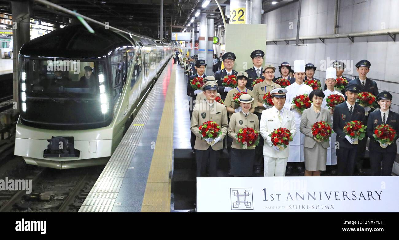 People pose for photograph in front of Train Suite Shiki-shima, the E001 series luxury sleeper ...