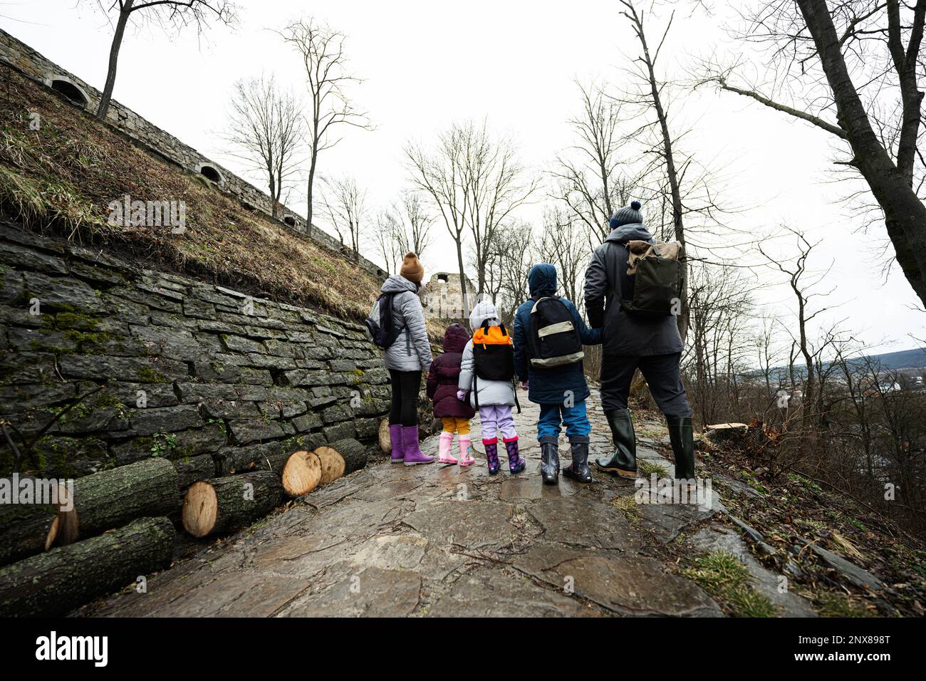 Back of family with three children stand on wet path to an ancient ...