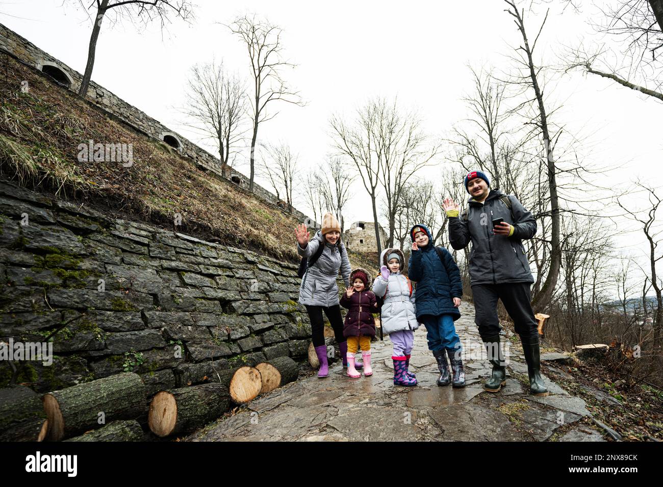 Family tourist with three children stand on wet path to an ancient ...