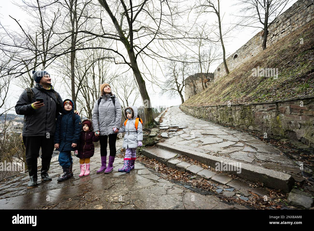 Family tourist with three children stand on wet path to an ancient ...