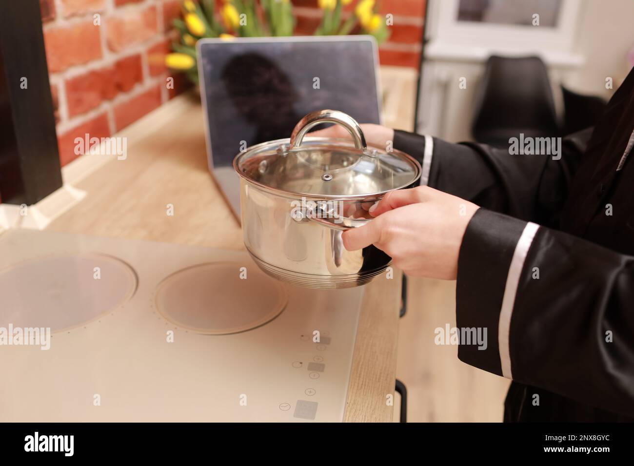 Cropped photo of woman's hands puts metal cooking pan on induction ...
