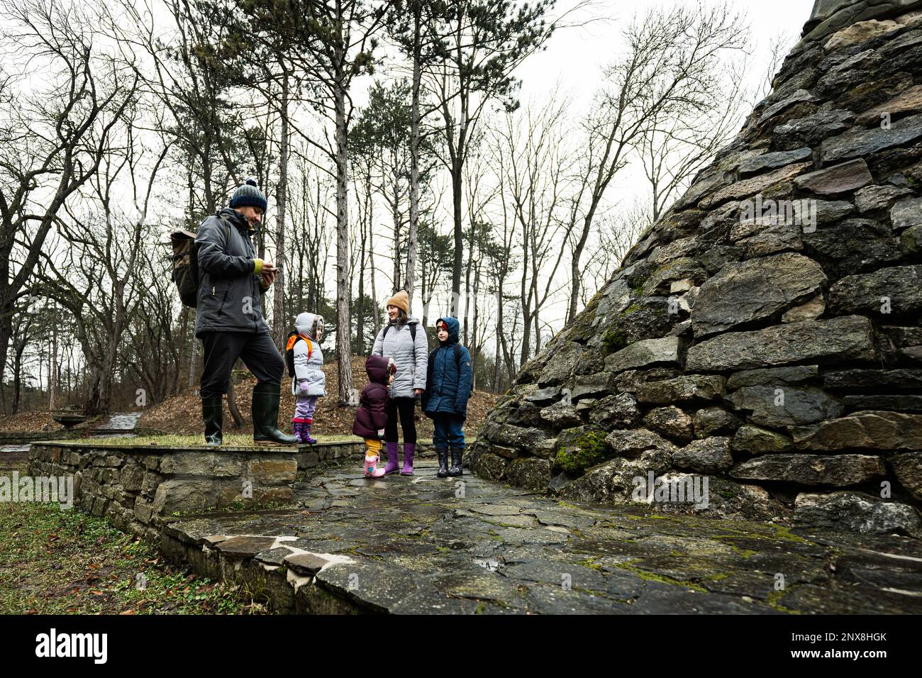 Family tourist with three children, stand near stone monument in forest ...