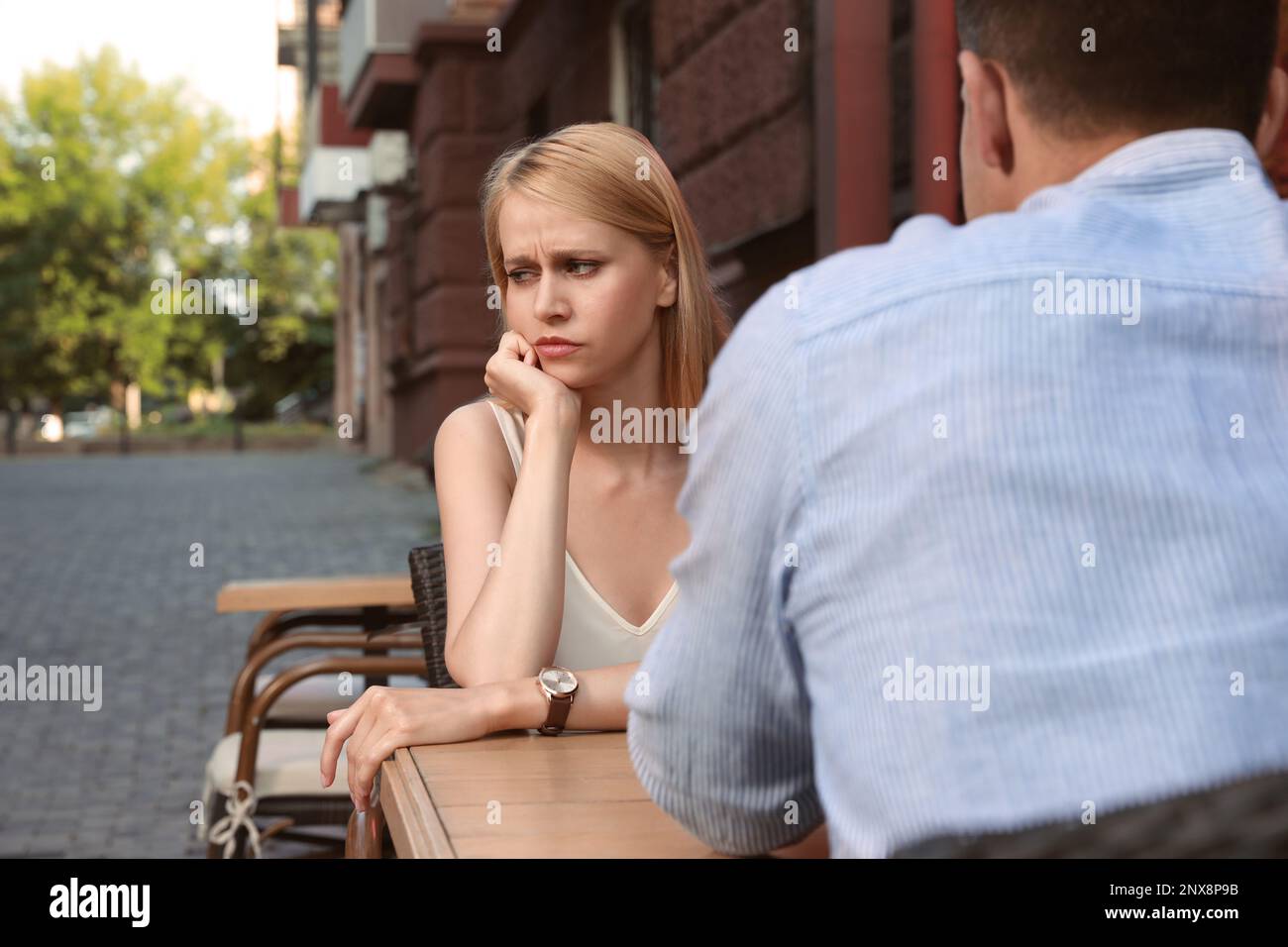Young woman having boring date with man in outdoor cafe Stock Photo - Alamy