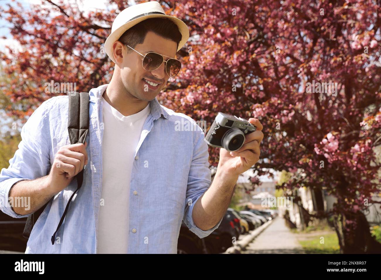 Tourist with camera walking on city street Stock Photo - Alamy