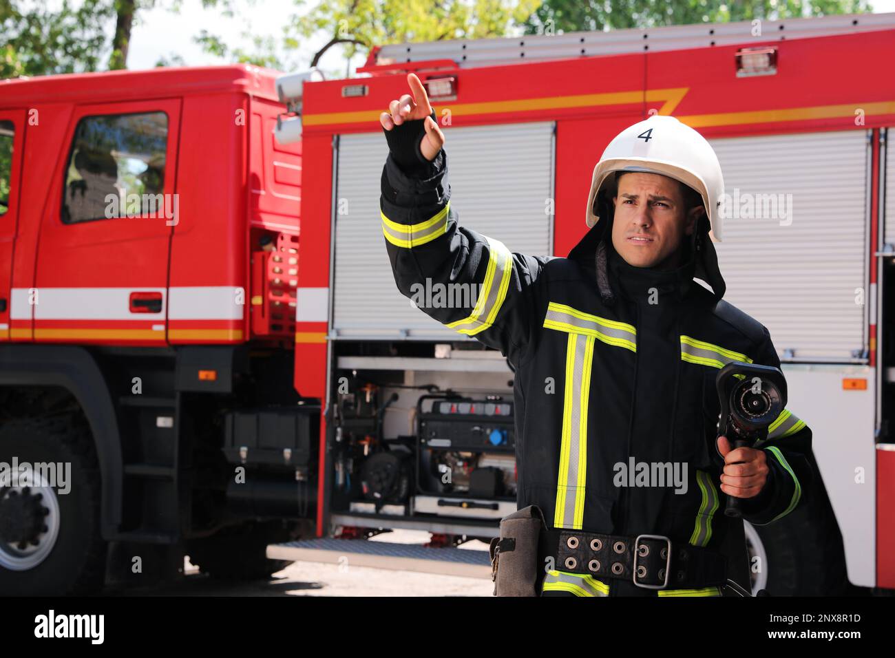 Firefighter in uniform with high pressure water jet near fire truck ...