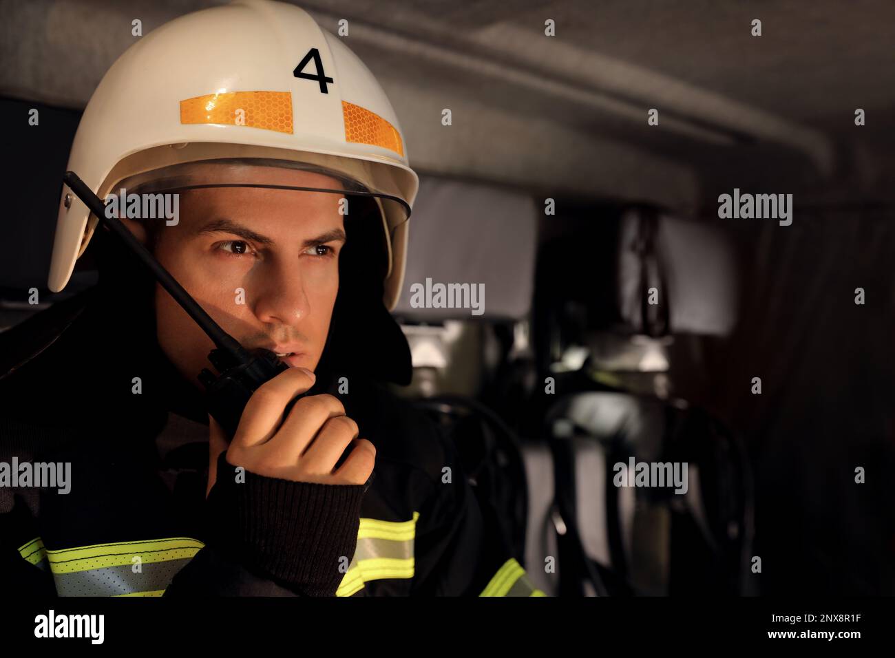 Firefighter using portable radio set in fire truck, space for text ...