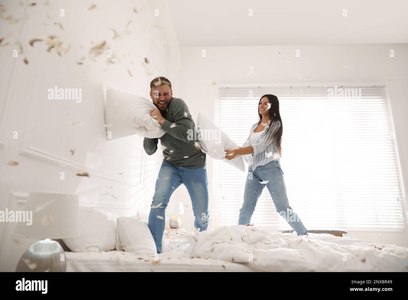 Happy young couple having fun pillow fight in bedroom Stock Photo - Alamy